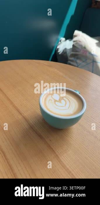 Camera slowly moves around a turquoise cup of lactose free latte on a ...