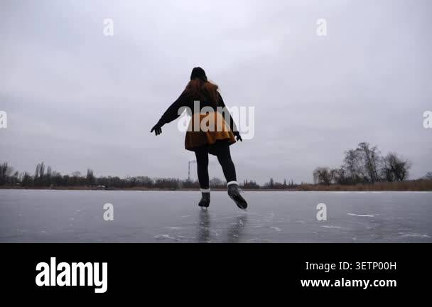 Young girl skating on ice rink at nature. Female skater shod in figure ...