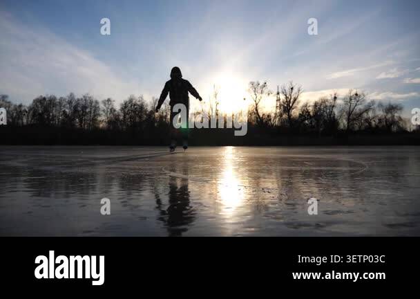 Young man shod in figure skates sliding on ice surface during beautiful ...