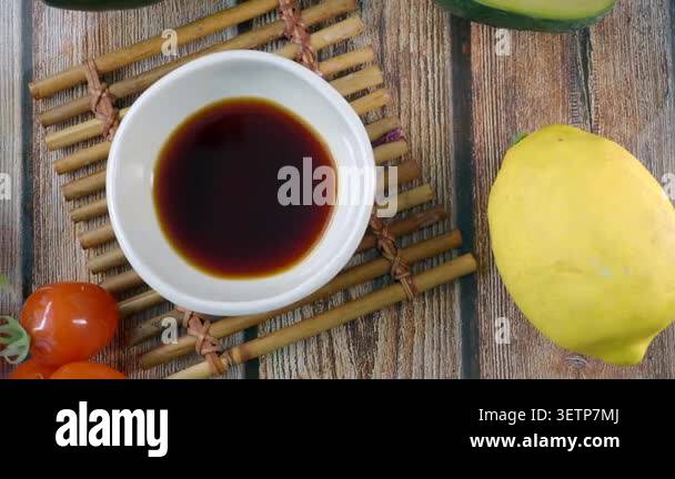 A plate shows a small bowl of soy sauce beside lemon and vegetables ...