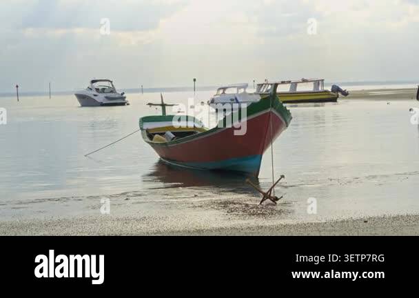 Boats anchor on calm waters at low tide, Ilha do Mel, Brazil, on a ...