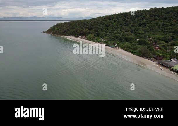 Aerial view of a beautiful sandy beach, gentle ocean waves, and a green ...