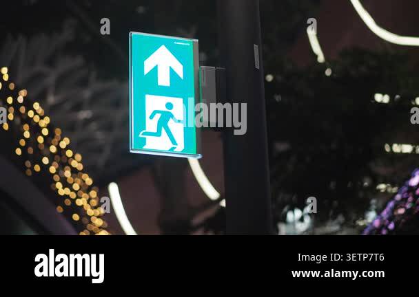 A sign points to an exit for people walking in a crowded area Stock ...