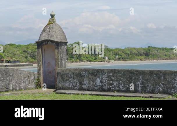 View of historic lighthouse, ocean, beach, and green forest at Ilha do ...