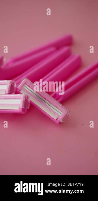 A set of pink razors is placed on a pink surface. They are ready for ...