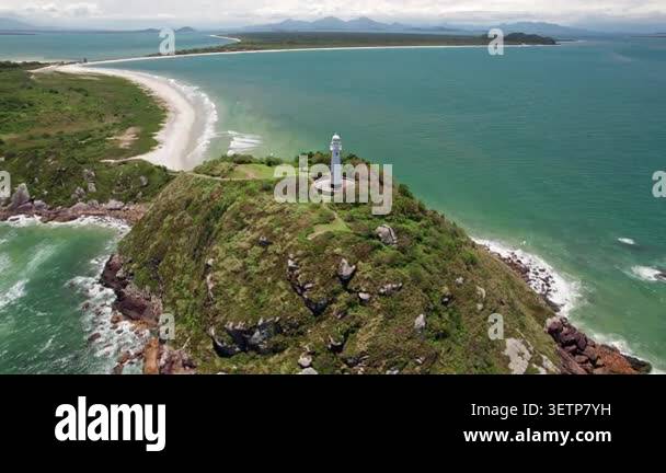 An aerial view showcases a lighthouse on a hill, surrounded by pristine ...
