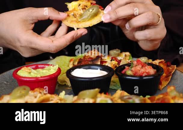 People are sharing nachos with guacamole, sour cream, and salsa Stock ...