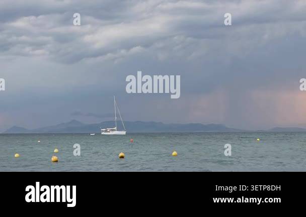 Single white sailboat floating peacefully offshore while thunderclouds ...