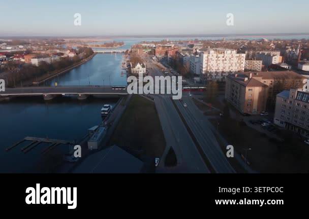 Aerial view shows wide river bisecting a coastal town, low bridge with ...
