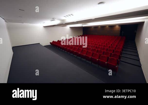 Empty modern lecture hall with uniform red seats and small stage ...