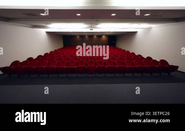 Empty auditorium with bright red seats and wooden paneled stage wall ...