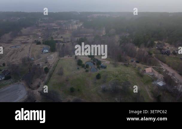 Aerial rural parcel with kidney shaped pond, cabins, and garden beds ...