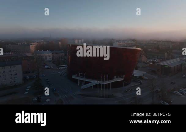 Aerial drone view shows rust colored elliptical cultural hall, tall ...