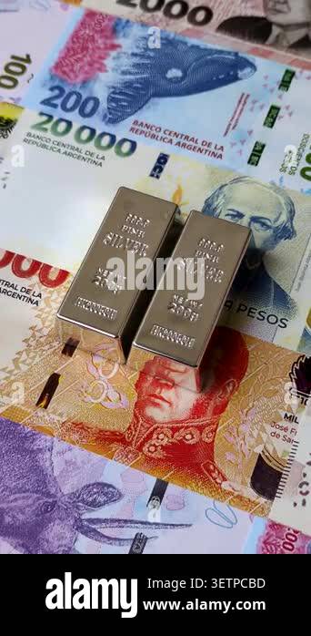 A silver bar, white metal against a backdrop of Argentine money, as a ...