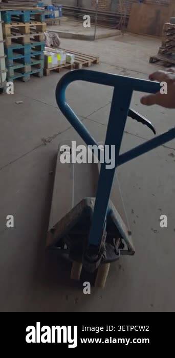 Pov of a warehouse worker pulling a manual pallet truck through an ...