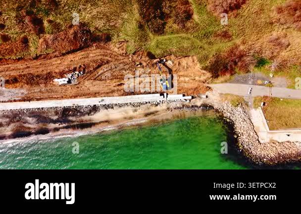 Aerial view of coastal seawall construction with excavator, Black Sea ...