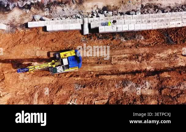 Workers installing concrete seawall blocks on eroded coast. Overhead ...
