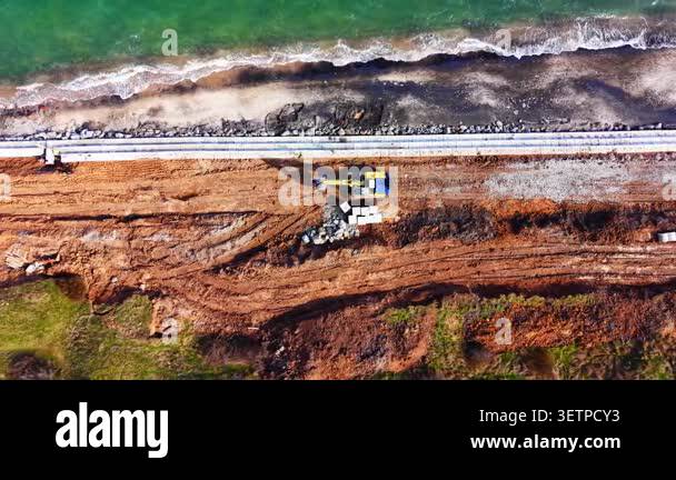 Aerial view of seawall construction with excavator and block placement ...