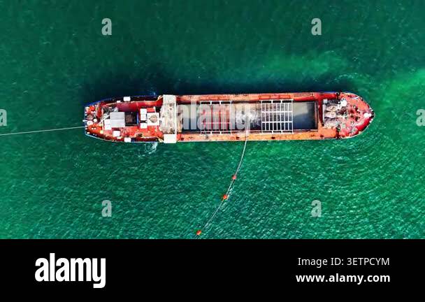 Red dredging barge anchored in turquoise sea. Aerial view of rust red ...