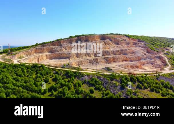 Open pit limestone quarry cut into a forest hill, Bulgaria. Panoramic ...