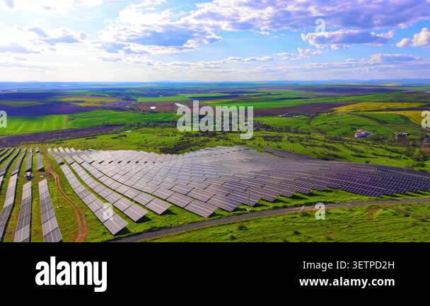 Solar panel array on rolling green hills, captured from a wide drone ...