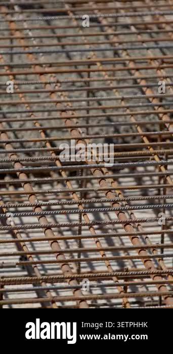 Vertical video. Pouring wet cement mixture into rusty steel rebar ...