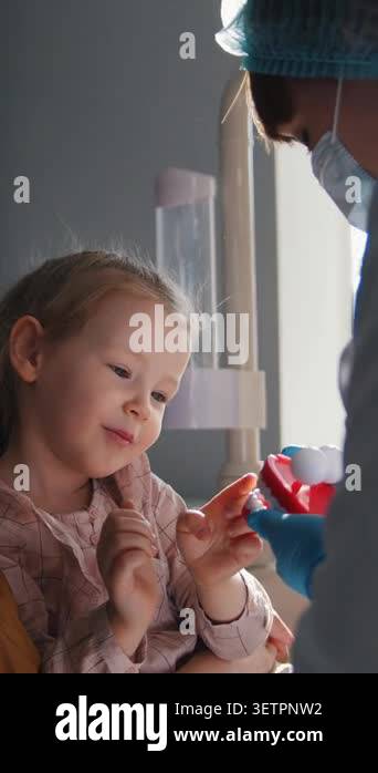 A girl sits in a dental office looking at the doctor. She appears happy ...