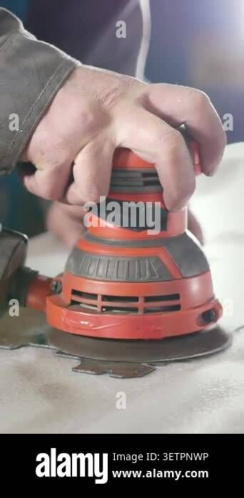 Manual sander sanding a metal detail at the factory, industrial concept ...