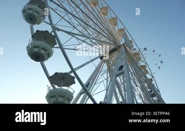 Giant white Ferris wheel spinning against a clear blue sky at a ...