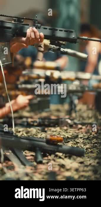 Several hands inspecting various modern automatic rifles and sniper ...