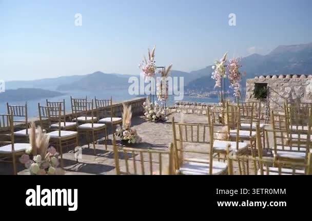 Oceanfront wedding ceremony setup with golden chairs, pastel floral ...