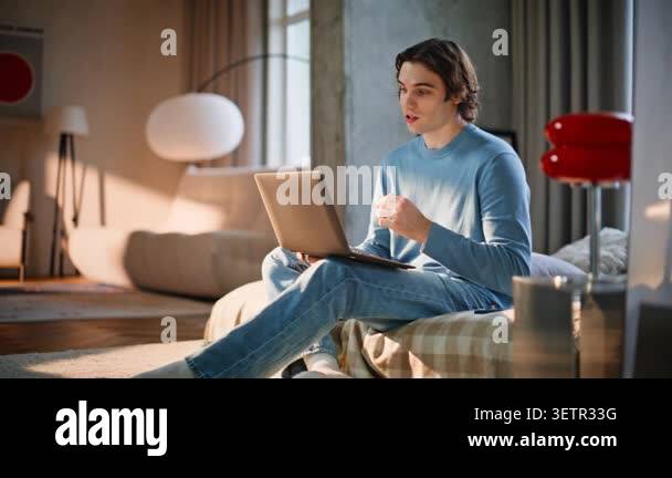 Young businessman talking laptop sitting bed early morning. Relaxed man ...