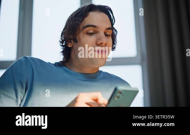 Closeup pensive guy holding cellphone choosing online purchase at home ...