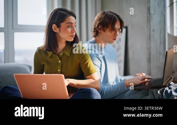 Enthusiastic pair creating startup at home sitting bed in cozy ...