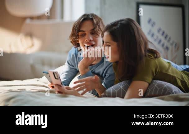 Lying teenagers watching phones social media content relaxing at bed ...