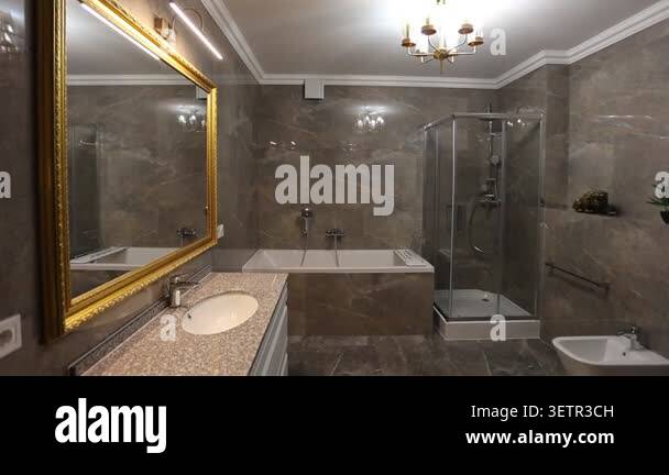 Slow interior view presents spacious clean bathroom with gold framed ...