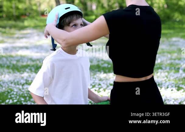 Mother helping her young son put on a bicycle helmet before riding ...