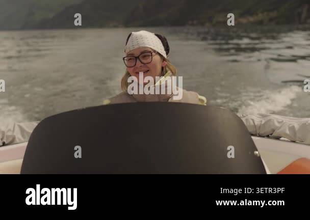 Young woman wearing glasses and a headscarf while enjoying a boat ride ...