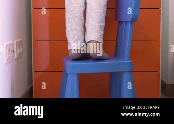 A little boy on tiptoe trying to reach something in his bedroom. Close ...