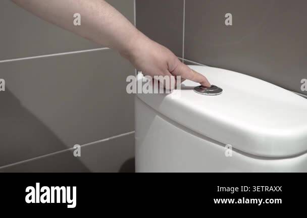 Closeup of female hand pushing a button to flush a close tool a ...