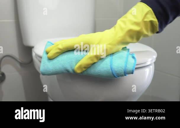 Close up of hand in a yellow rubber glove with blue rag cleaning the ...