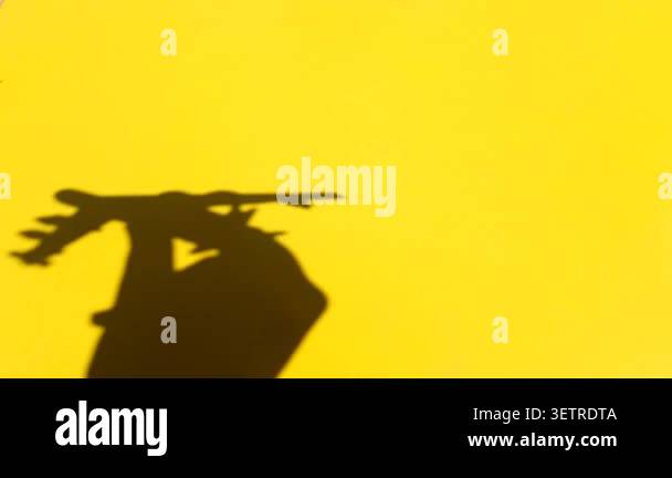 A hand holding a toy airplane casts a dramatic shadow on a vivid yellow ...