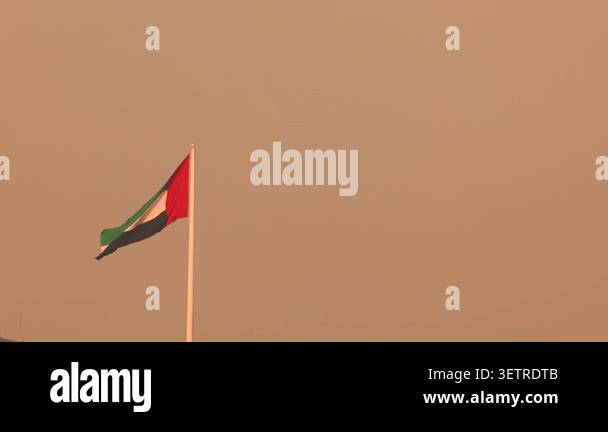 United Arab Emirates flag waving against warm golden sky at sunset ...