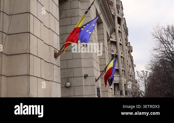 Romanian and European Union flags waving in the wind on the facade of a ...