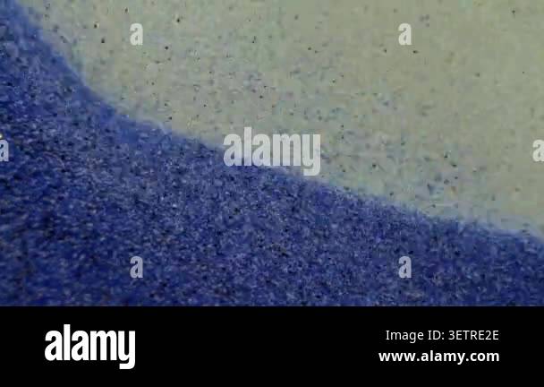 Macro video of blue sand flowing inside an hourglass, revealing texture ...