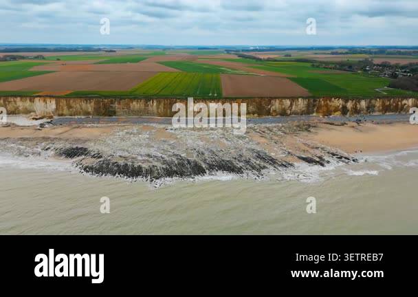 Drone shot of chalk cliffs rising above beach on Normandy coast. Broad ...