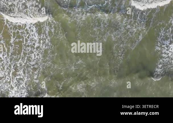 Aerial top down footage of sea water with foamy wave bands and moving ...