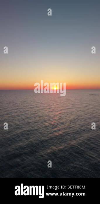 Vertical cinematic drone footage capturing a bright yellow sun rising ...