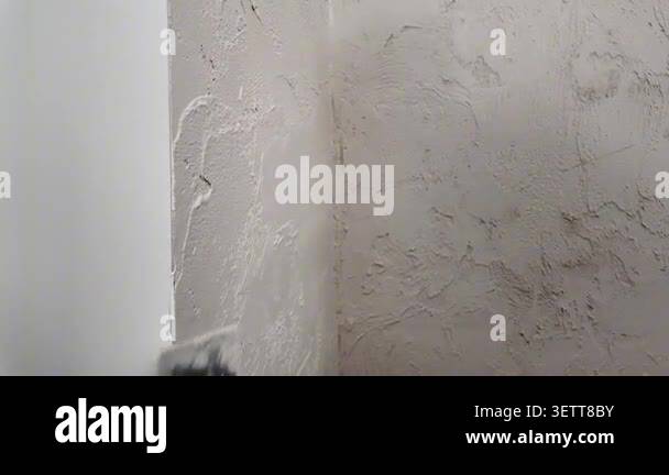 A worker applies plaster to a wall using a trowel. The process shows ...