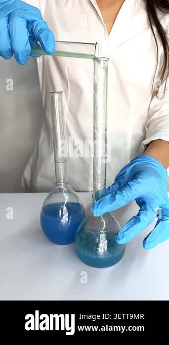 A person conducts an experiment by mixing two liquids in a laboratory ...